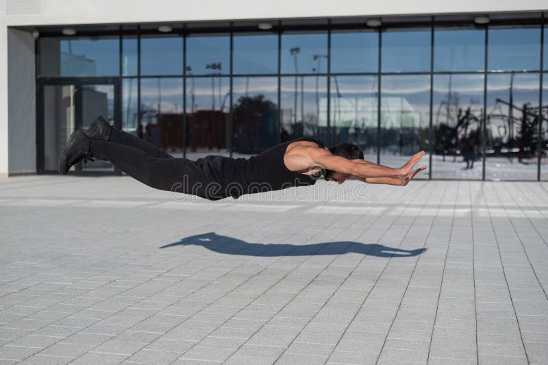 A Man in Black Sportswear Jumps while Doing Push-ups Outdoors. Stock ...