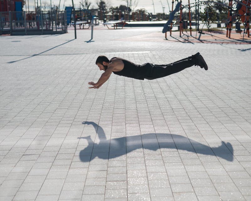 A Man in Black Sportswear Jumps Doing Push-ups in the Park. Stock Photo ...