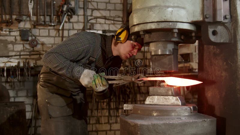 A Man Blacksmith Forming a Knife Using an Industrial Pressure Machine ...