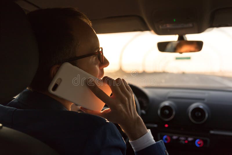 Man in Blazer Using and Talking on Smartphone while Driving a Car at ...