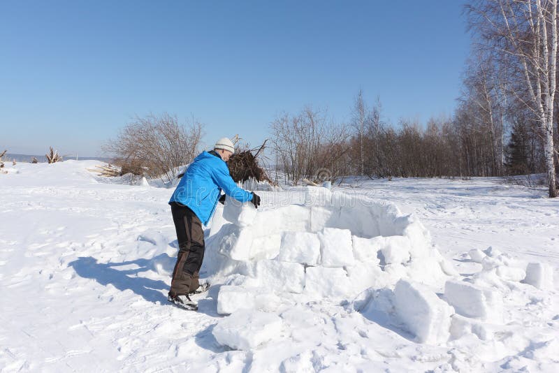 Man in a Blue Jacket Building an Igloo on a Glade Stock Photo - Image ...