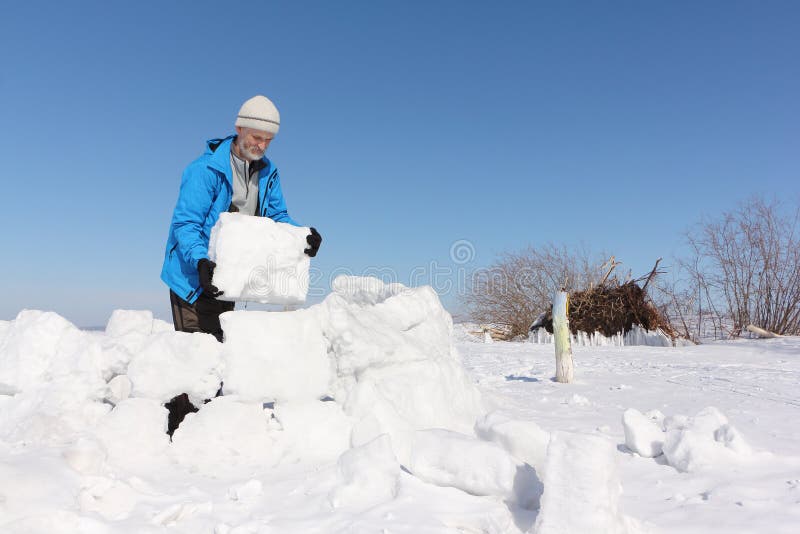 Man in a Blue Jacket Building an Igloo on a Glade Stock Photo - Image ...