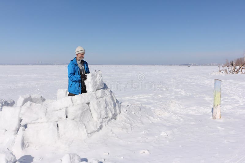 Man in a Blue Jacket Building an Igloo on a Glade Stock Photo - Image ...