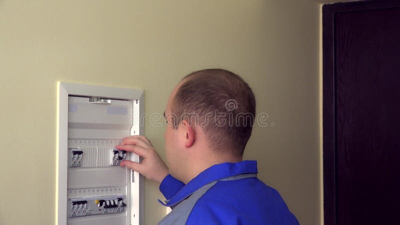 Man in Blue Uniform Turn on Circuit Breakers on Panel Box at Flat House ...