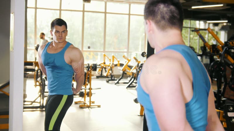 Man Bodybuilder Posing and Shows Muscles Near Mirror in the Gym Stock ...