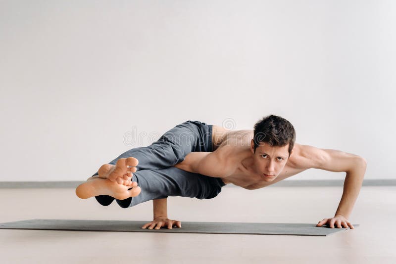 A Man with a Bony Torso Trains Lying Down, Doing a Handstand in the Gym ...