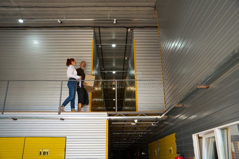 Man with a Box and a Woman Walk through Warehouse Stock Image - Image ...