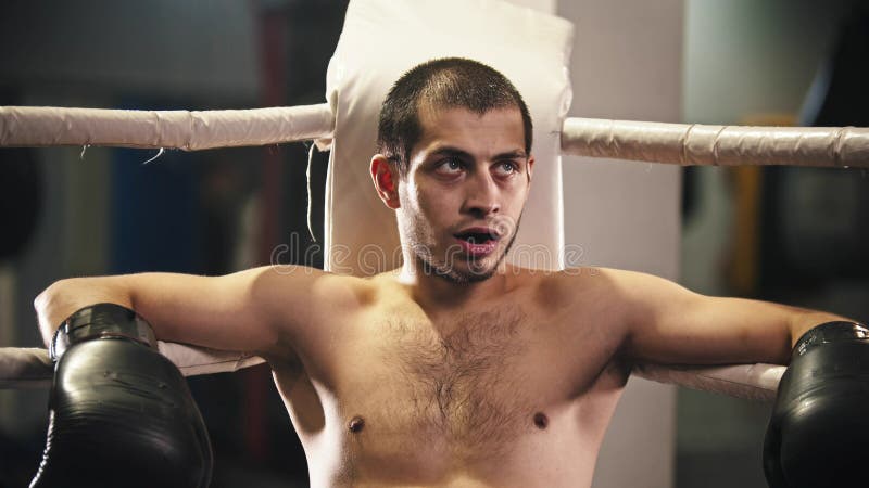 A Man Boxer Sitting in the Corner of the Ring with a Teeth Guard in the ...