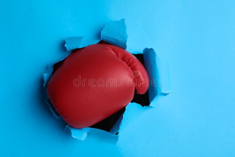 Man Breaking through Light Blue Paper with Boxing Glove, Closeup Stock ...