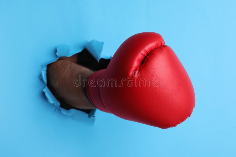 Man Breaking through Light Blue Paper with Boxing Glove, Closeup Stock ...