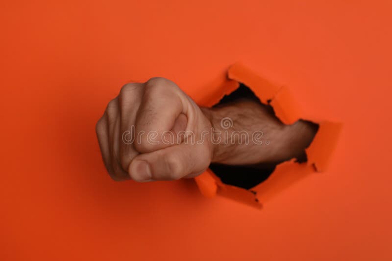 Man Breaking through Orange Paper with Fist, Closeup Stock Photo ...