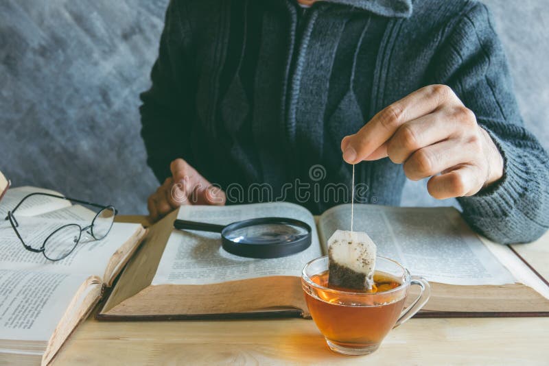 A Man Brewing Tea Bag with Glass of Tea on Table in Reading Tim Stock ...