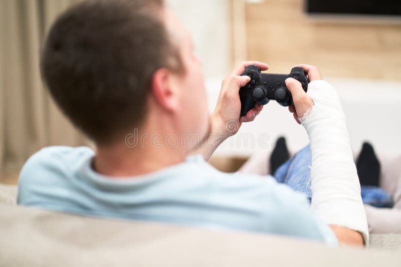 Man with Broken Arm in Plaster Cast Holding Controller and Playing in ...