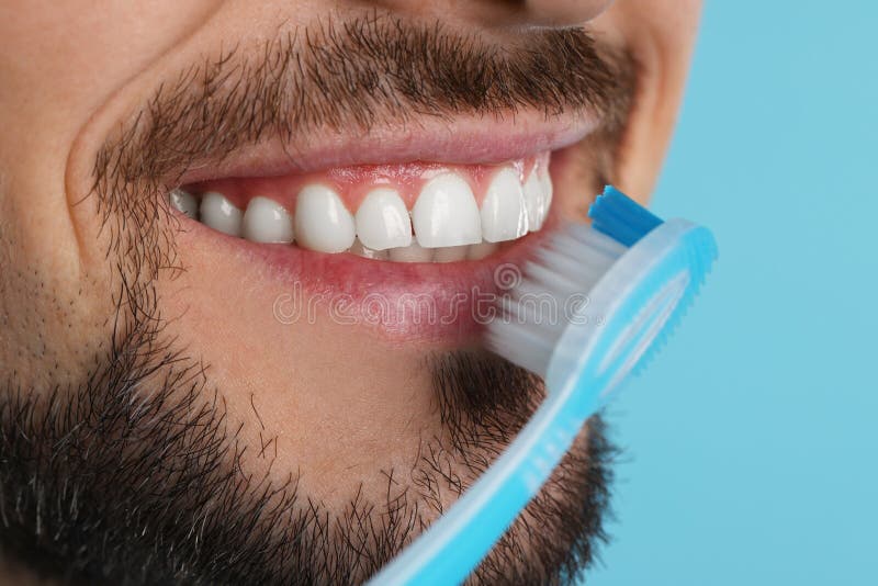 Man Brushing His Teeth with Plastic Toothbrush on Light Blue Background ...