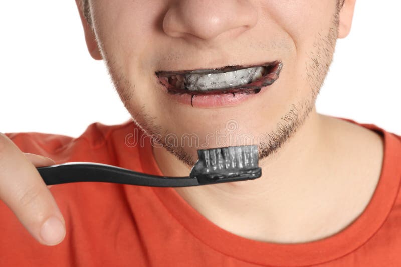 Man Brushing Teeth With Charcoal Toothpaste On White Background