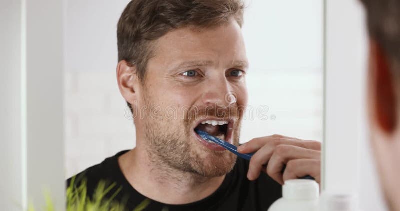Man Brushing Teeth in Front of a Mirror, Reflection Shows Full Face ...
