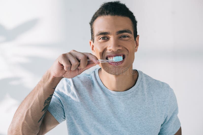 Man Brushing Teeth with Toothbrush and Looking at Camera Stock Photo ...