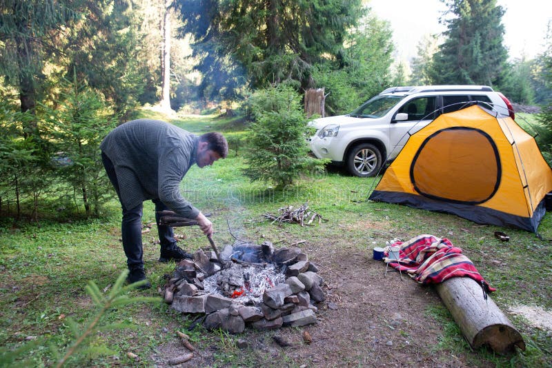 Man Build Fire In Forest, Car With Yellow Tent On Background Stock ...