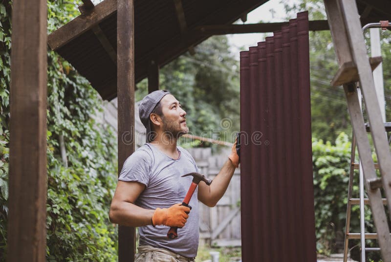 Man Building Roof and Holding Hammer and Roof Material. Stock Photo ...