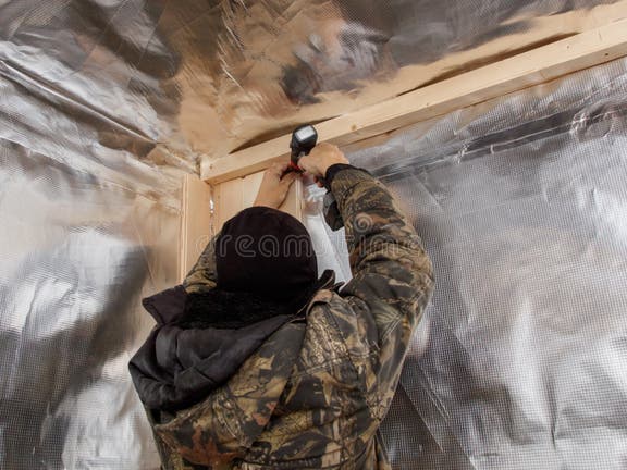 A Man in a Camo Jacket is Working on a Project in a Room with a Silver ...
