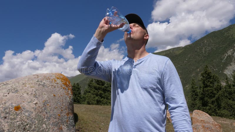 Man in Cap Drinking Water from Bottle on Mountain and Blue Sky ...