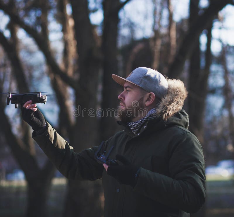Man in cap piloting drone stock image. Image of quadrocopter - 169392539