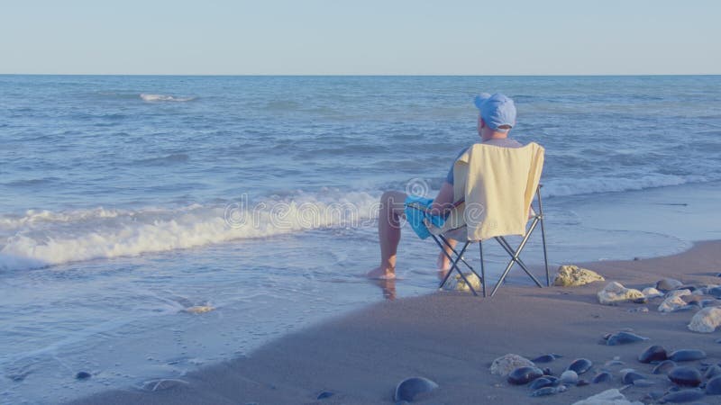 Man in a Cap is Relaxing on the Beach, Sitting on a Sun Lounger Stock ...