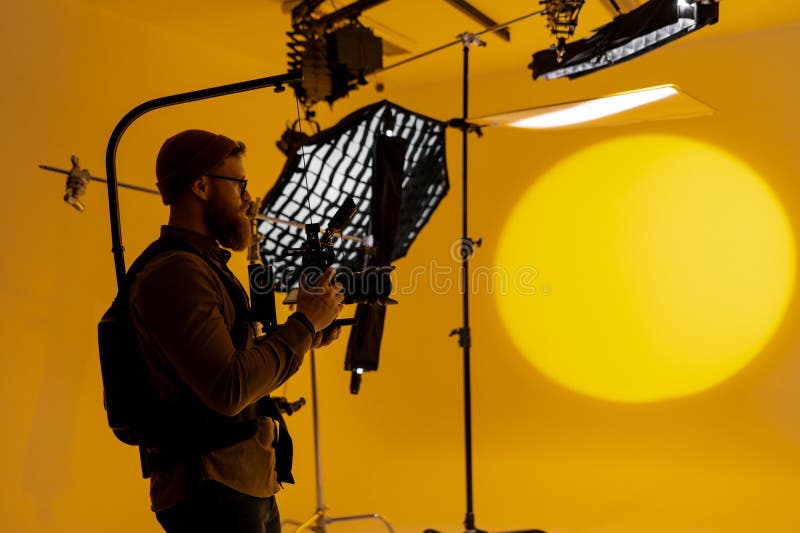Man Capturing Large Yellow Background with Camera at Film Studio. Stock ...