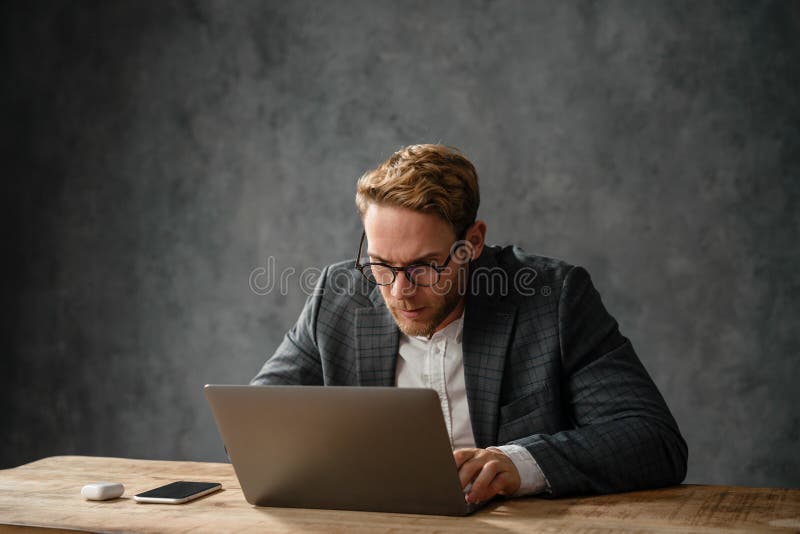 A Man Carefully Reading Something from a Laptop Screen in the Studio ...