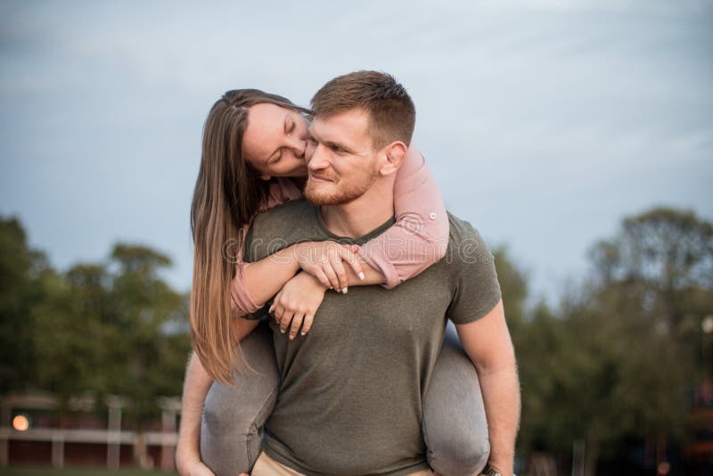 Man Carries His Girlfriend On His Back While She Kisses Him On The