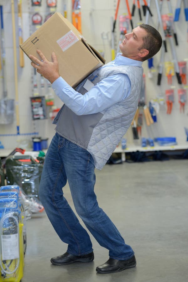 Man Carrying Heavy Cardboard Box in Warehouse Stock Photo - Image of ...