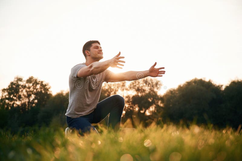 Man in Casual Clothes is Sitting on the Ground of Field with Arms Open ...