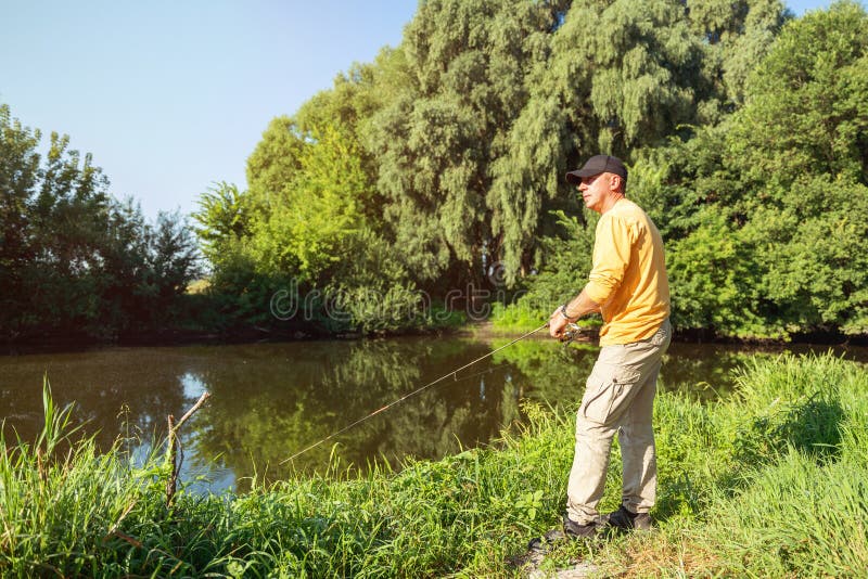 A Man Catches Fish with a Spinning Rod on the River Bank Stock Image ...