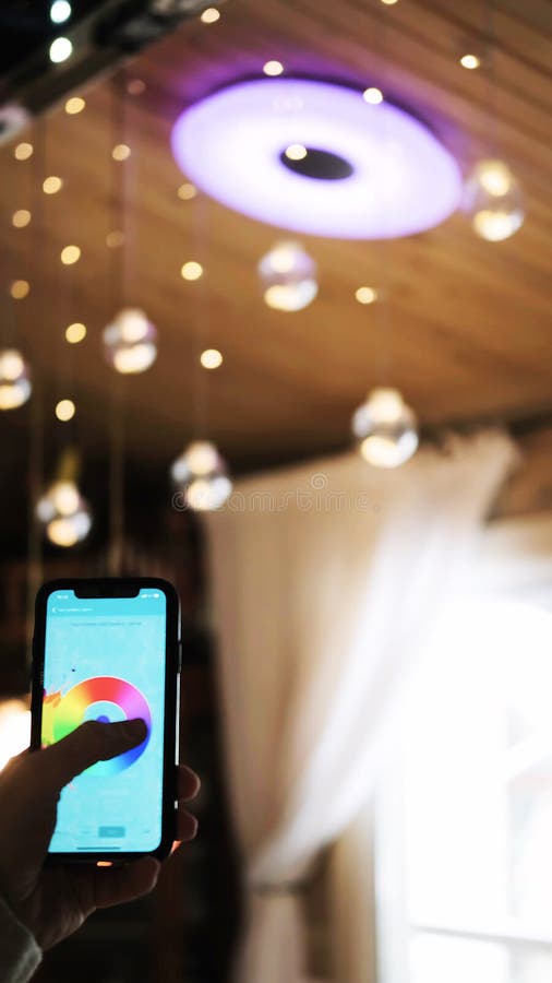 A Man Changes the Color of a Lamp Using a Mobile App Stock Photo ...