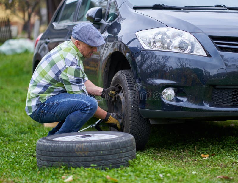 Man changing a flat tyre stock photo. Image of male - 202647012