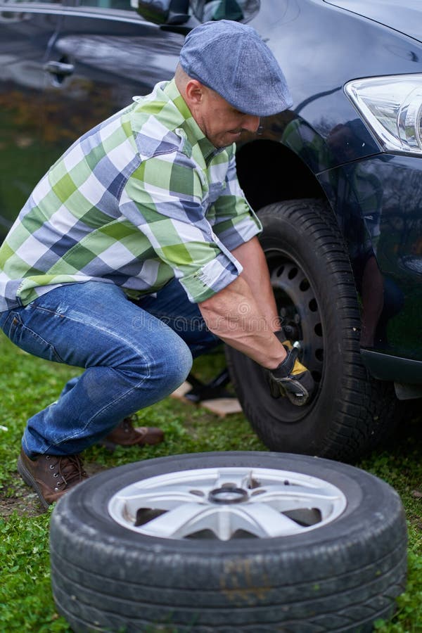 Man changing a flat tyre stock photo. Image of tool - 202647016
