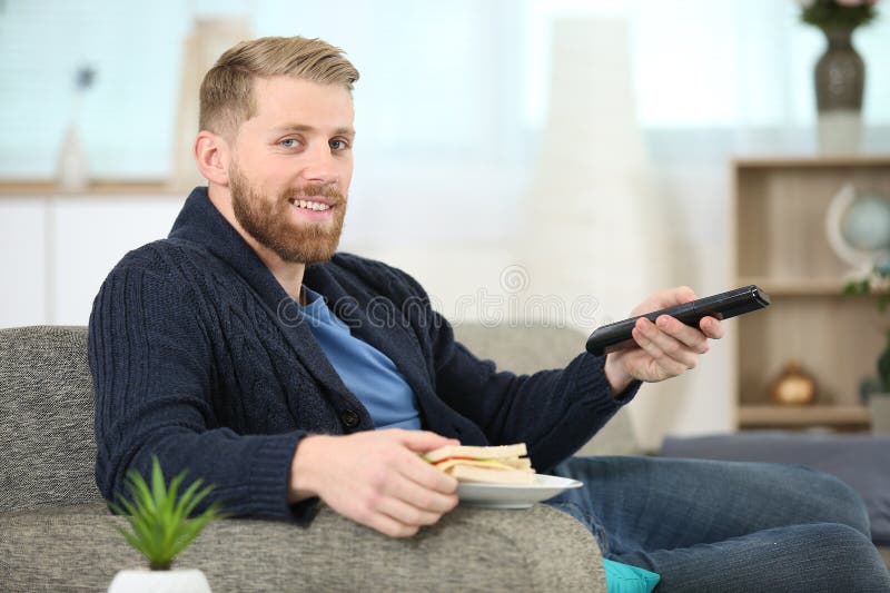 Man Changing Tv Channel with Remote Control while Eating Sandwich Stock ...