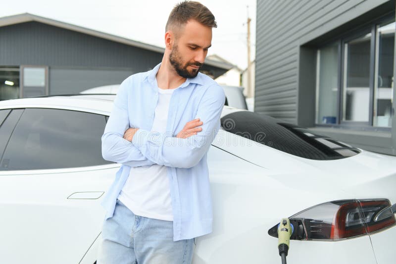 Man Charging Electric Car by the House. Stock Image - Image of ecology ...