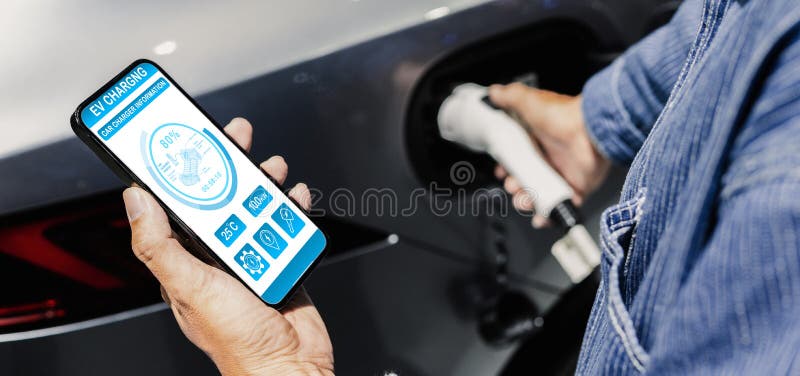 Man Charging Electric Vehicle with Cable Looking at App on Mobile Phone ...