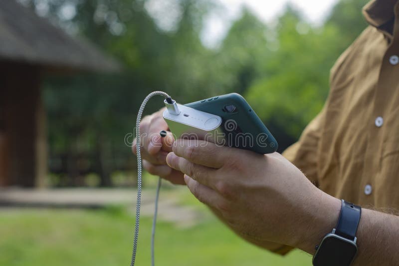 Man Charging Phone with Power Bank Outdoors, Mobile Technology in ...