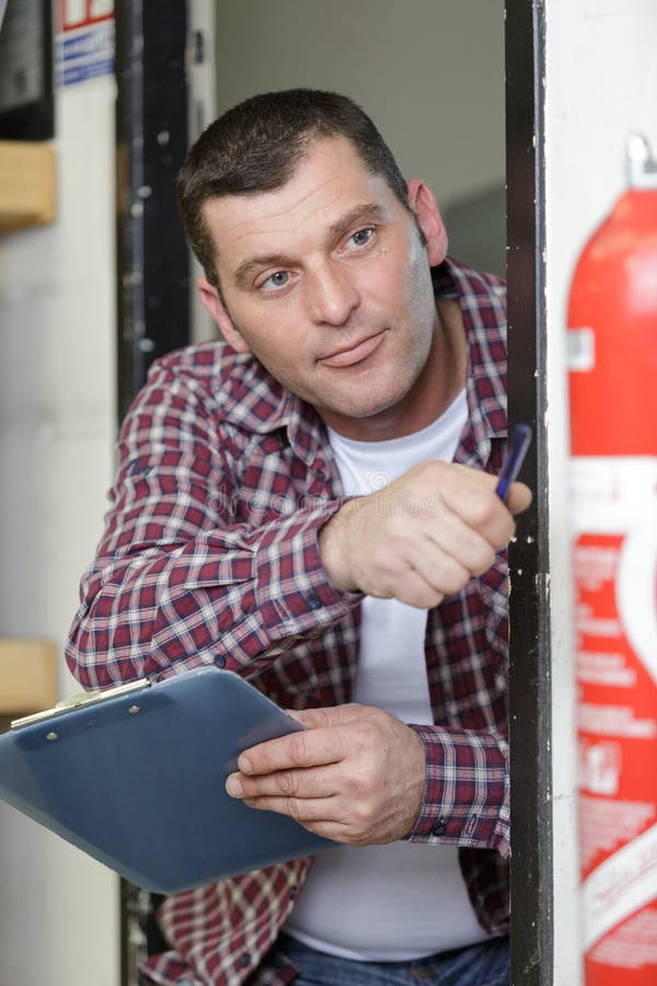 Man Checking Fire Extinguisher Writing on Document Stock Image - Image ...