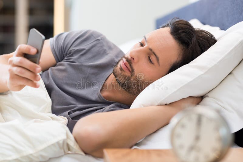 Man checking phone in bed stock image. Image of smartphone - 68277285