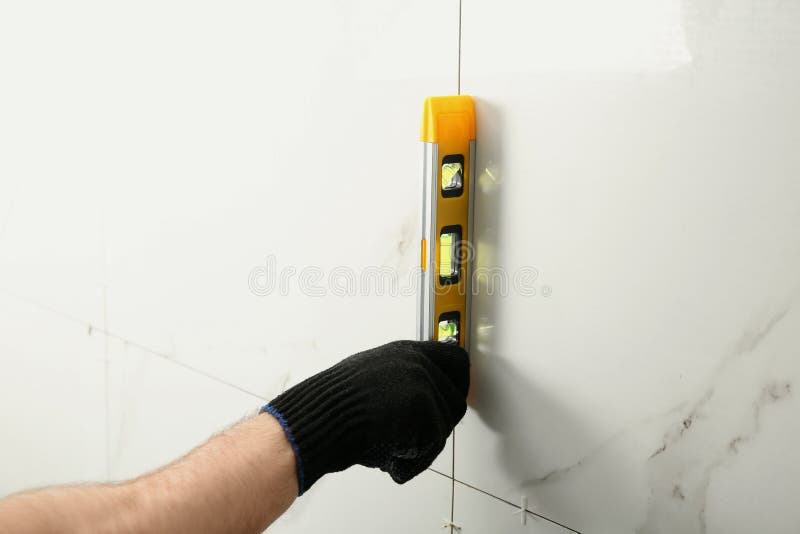 Man Checking Proper Ceramic Tile Installation with Level on Wall ...