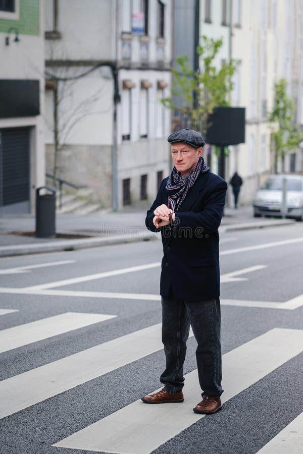 A Man Checking the Time on His Wristwatch while Standing at a Crosswalk ...