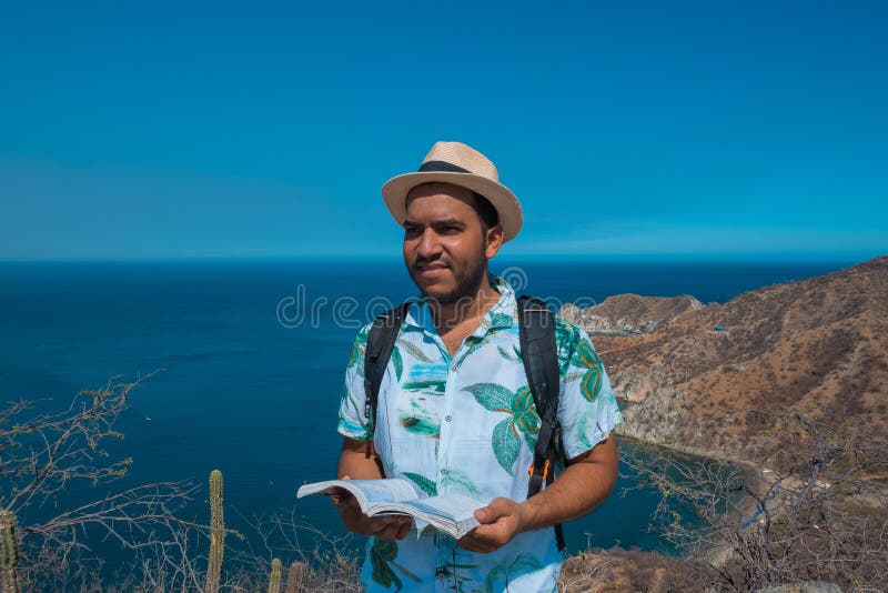 Man Checking Travel Guide on Top of a Mountain. Sea in the Background ...
