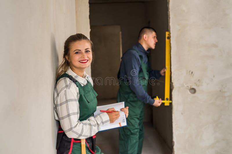 Man Checking Wall with Water Level Tool and Woman Writing Measurements ...
