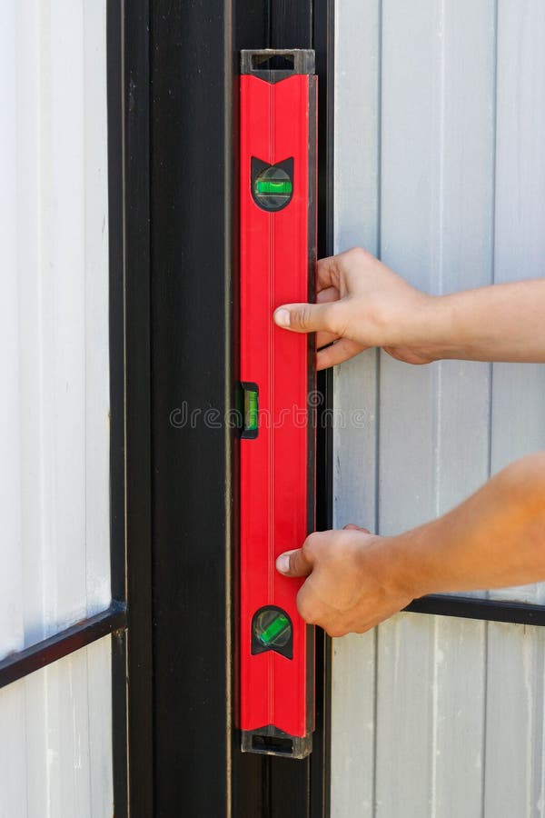 A Man Checks a Smooth Surface Level. Red Construction Level Stock Image ...