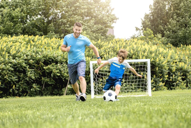 Man with Child Playing Football Outside on Field Stock Image - Image of ...