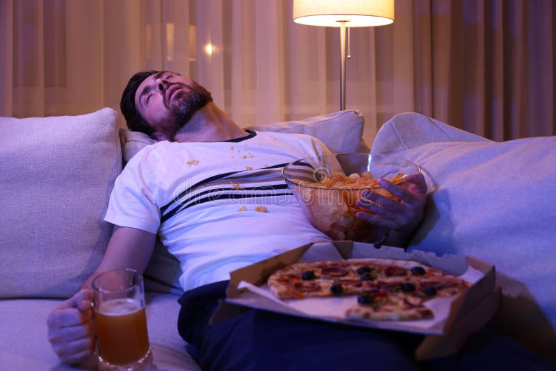 Man with Chips, Pizza and Glass of Beer Sleeping on Sofa at Night. Bad ...