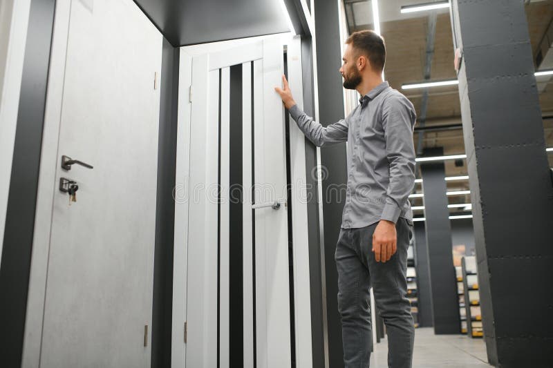 A Man Chooses a Door for the House. Buying a Door at a Hardware Store ...